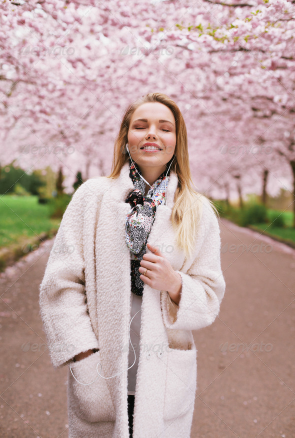 Relaxed young woman taking a walk at spring garden Stock Photo by jacoblund
