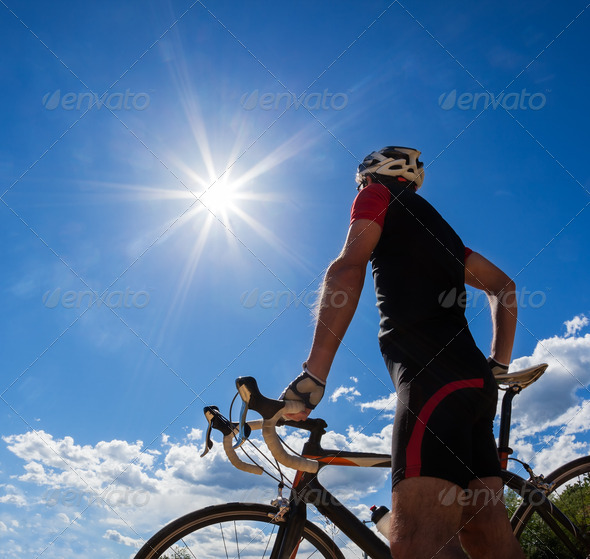 Road cyclist resting on his bike. Backlight, sunny summer day. Stock ...