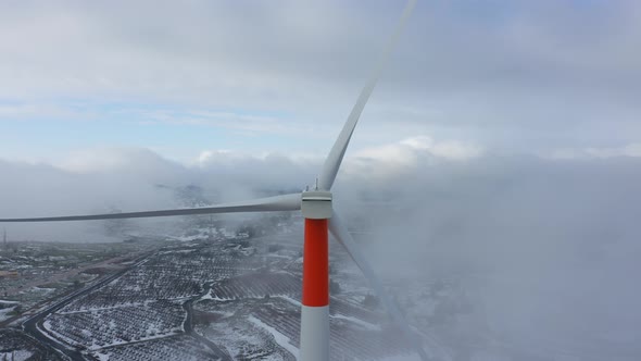 Wind turbine in a snowy landscape with early winter morning mist ...