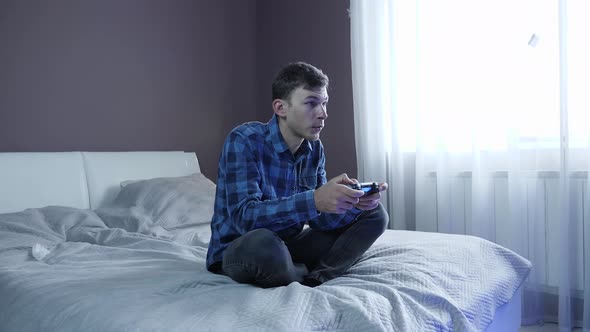 Excited gamer boy sitting on couch, playing video games on console ...