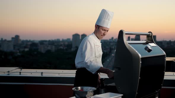 A professional Chef prepares a barbecue on the rooftop of a skyscraper ...