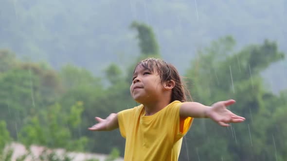Cute little girl having fun catching rain drops. Kids play in summer ...