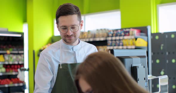 Young Cashier in Glasses Servicing Young Woman Customer in Supermarket ...