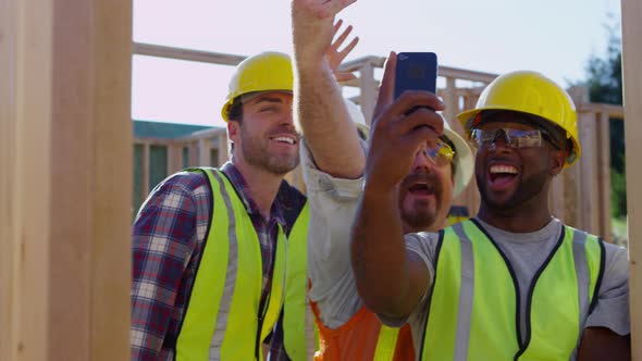 Group of construction workers taking selfies and goofing off with cell ...
