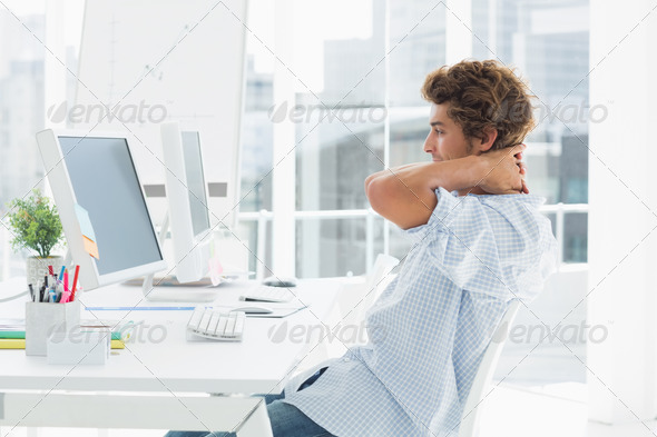 Side view of a casual young business man using computer in a bright ...