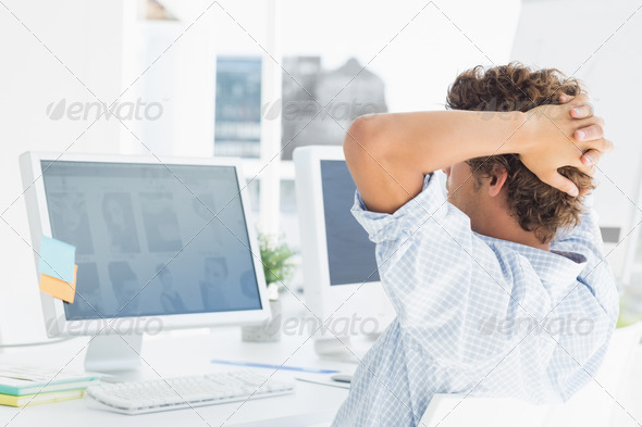 Rear view of a casual young business man using computer in a bright ...