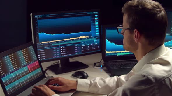 Trader working in office at night using workstation and analysis ...