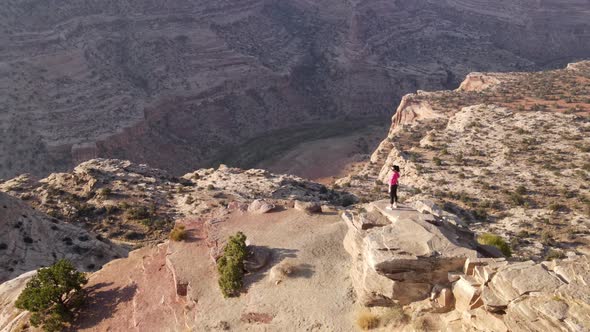 Aerial woman hiking on the edge of the San Rafael River Canyon in Utah ...