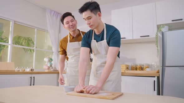 Asian young LGBTQ male gay family enjoy bake bakery in kitchen at home ...