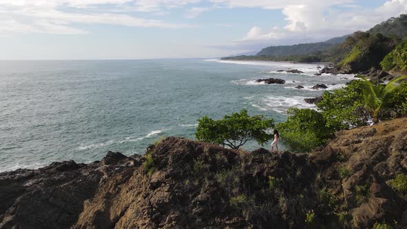 Lady walking on cliff edge with view of ocean in Costa Rica. Aerial ...