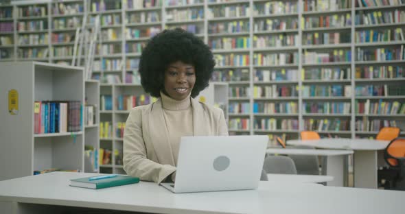 Young Librarian Works on Laptop Sitting at Desk in Library, Stock Footage