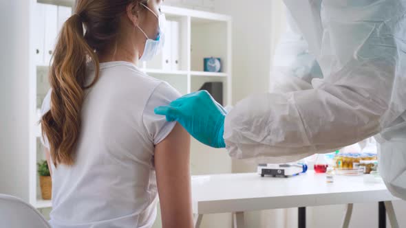 Doctor in Ptotective Costume Making a Vaccine Injection to a Female ...