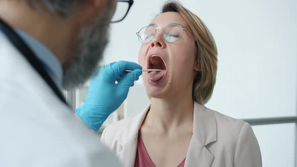 Young Woman Opening Mouth Showing Throat During Medical Exam with Male ...