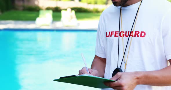 Smiling lifeguard writing on clipboard at poolside, Stock Footage ...