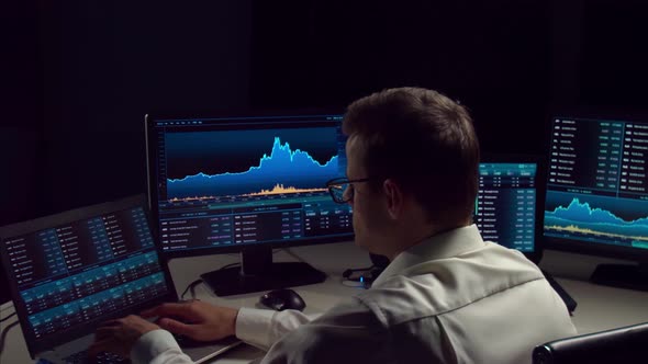 Trader working in office at night using workstation and analysis ...