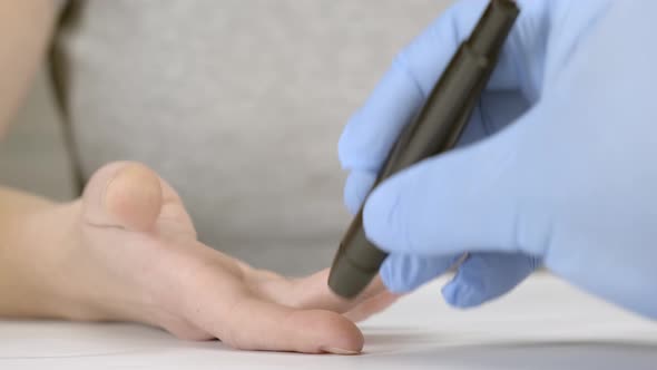 doctor makes puncture with lancing device in finger of female patient ...