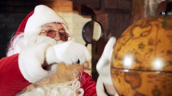 Santa looking into a globe through the magnifying glass., Stock Footage