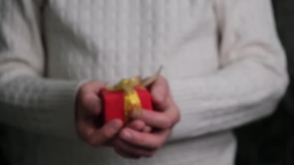 closeup of a man's hands holding out a red gift box. gift giving ...