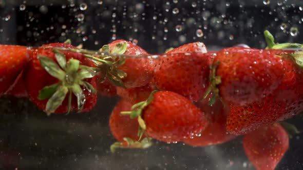 Vibrant strawberries falling and floating in aquarium full with water ...