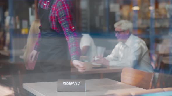 View Through Window of Waiter Put Reserved Sign on Table in Cafe, Stock ...