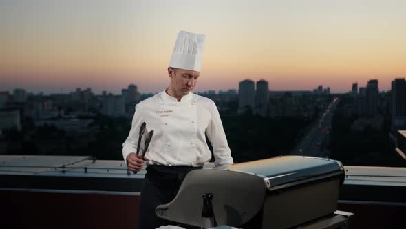 A professional Chef prepares a barbecue on the rooftop of a skyscraper ...