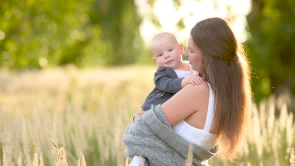 Loving tender mum in a dress with a cute little baby on a field at ...