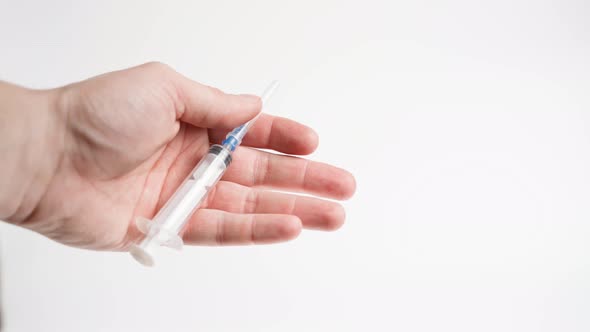 A Hand Squeezes a Medical Syringe with a Closed Needle on a White ...