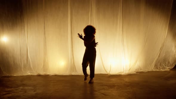 Professional Dancer Performing Against Stage Curtain with Warm Backlit ...