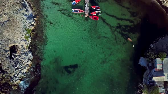 Dolly in overhead view of a small wooden walkway with fishing boats on ...