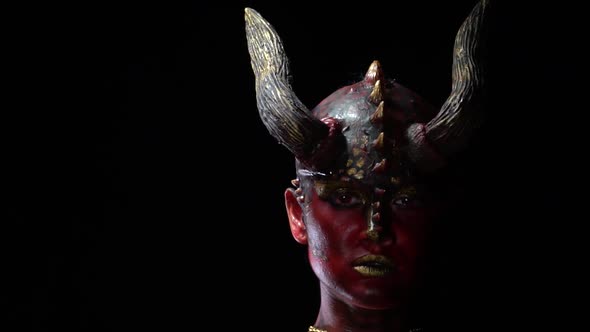 Close up of a scary demon with red skin and eyes, and some spikes on ...