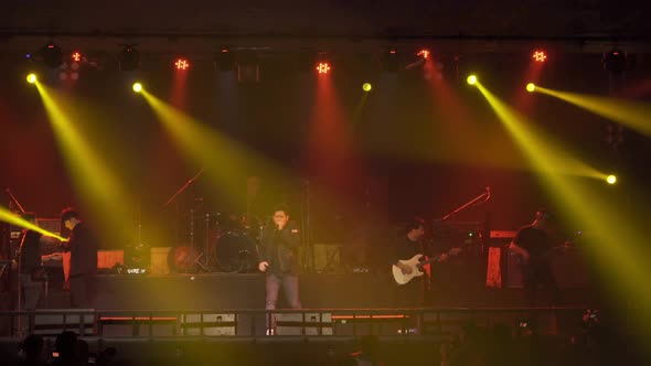 A singer with music band performing on a stage concert with lighting ...