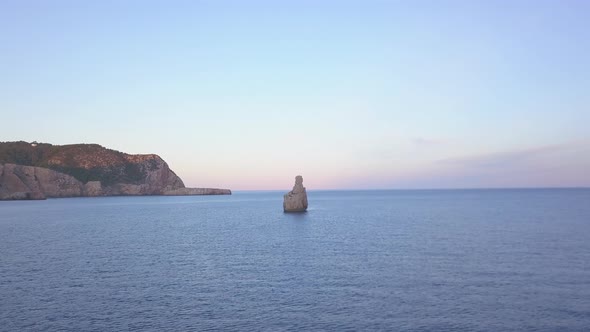 Aerial traveling shot of the iconic Ibiza rock Benirrás on a beautiful ...