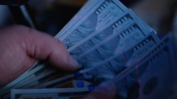 Checking one hundred dollar bills with an ultraviolet lamp. Fraud crime ...