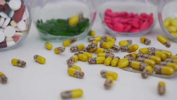 Slowly dropping capsules over a white table with colorful tablets in ...