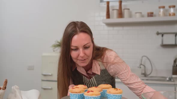 Caucasian woman action of get good smell from cupcakes on plate in the ...