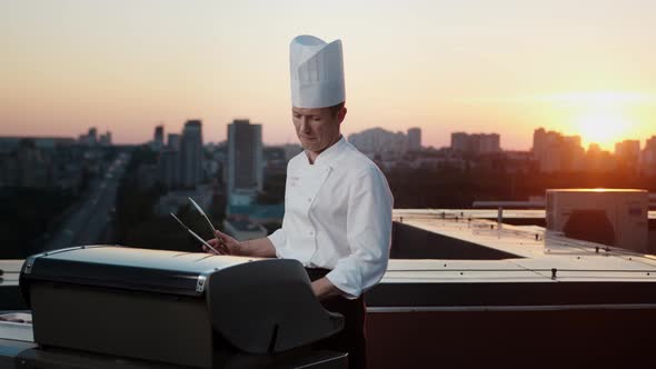 A professional Chef prepares a barbecue on the rooftop of a skyscraper ...