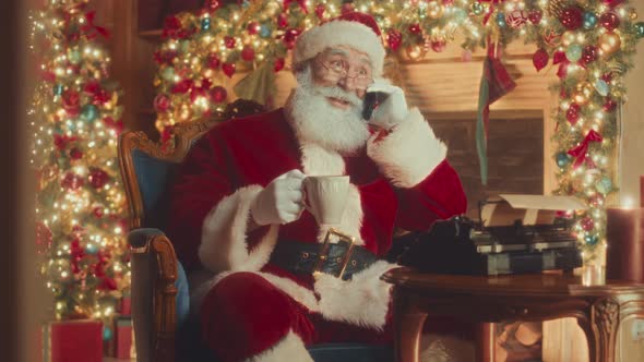 Santa Talking on Mobile Phone in Chair on Christmas Eve, Stock Footage