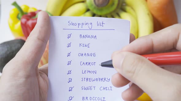 Hands hold shopping list checking with variety of colorful fresh fruits ...