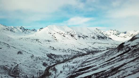 Flying in a winter valley with road and creek below., Stock Footage