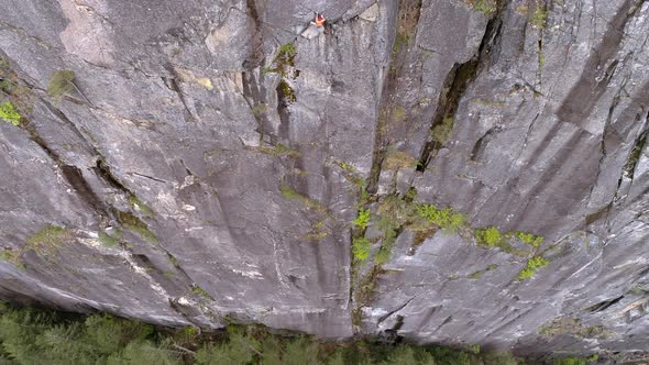 Aerial Reveal Of Rock Climber High Up Mountain Cliff With Birds Eye ...