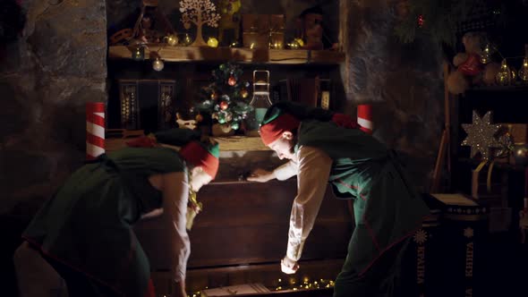 Curious elves in small decorated room opening the magic box. Two elves ...