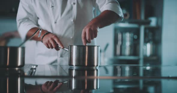 Chef calmly stirs pot while chef 2 moves in background, Stock Footage