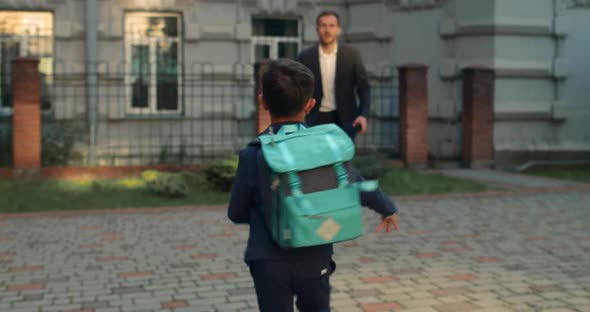 Backside View of Little Boy with Backpack Running in His Father Embrace ...