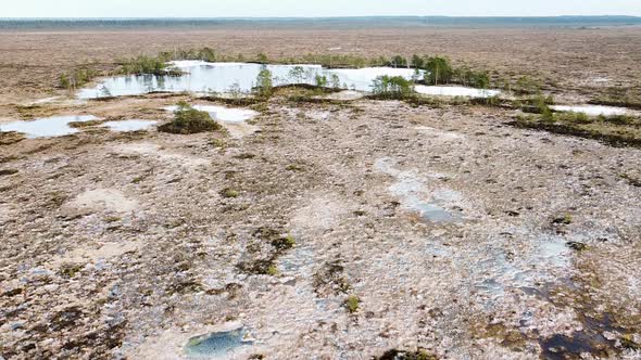 Rising aerial drone view of a group of frozen bog lakes in the middle of a barren landscape ...