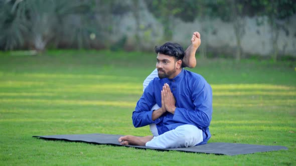 Indian man doing the Leg over Shoulder Yoga Pose or Eka Pada Sirshasana ...