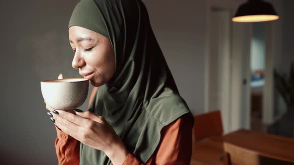 Happy Muslim woman wearing hijab sniffing tea, Stock Footage | VideoHive