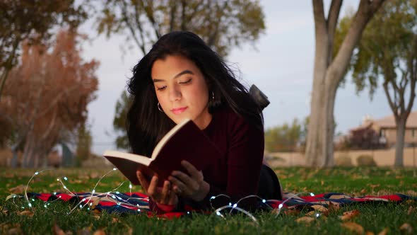 An attractive young woman opening the pages of a book and reading a ...