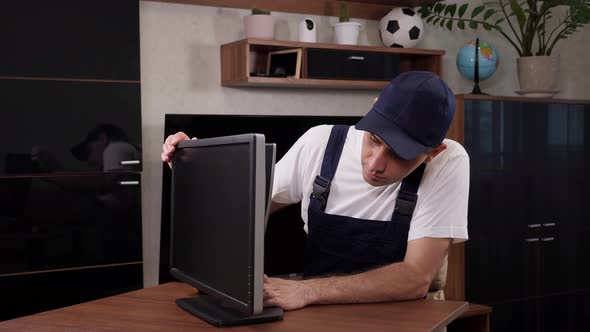 Closeup of a Male Handyman in Overalls Repairs a Computer Monitor ...