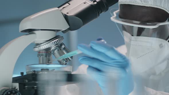 Black Lab Worker in Protective Suit Pouring Liquid under Microscope ...