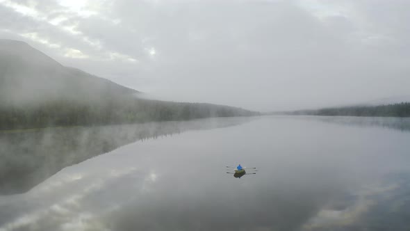 Dreamy landscape with a fog over water and person rowing a boat in ...